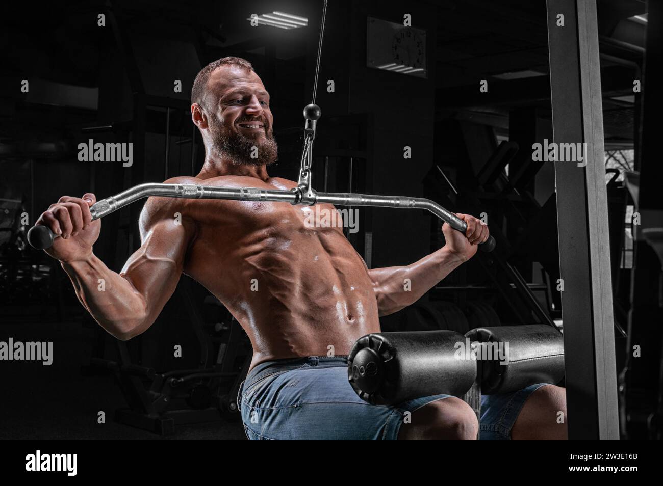 Professional athlete performs an exercise in the gym. Pulls the bar to ...