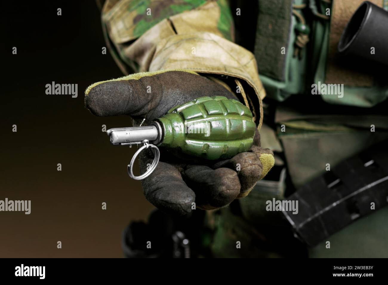 The soldier in full combat ammunition holds a grenade in his hand ...