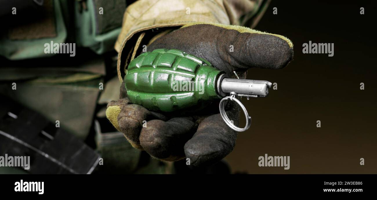 The soldier in full combat ammunition holds a grenade in his hand ...