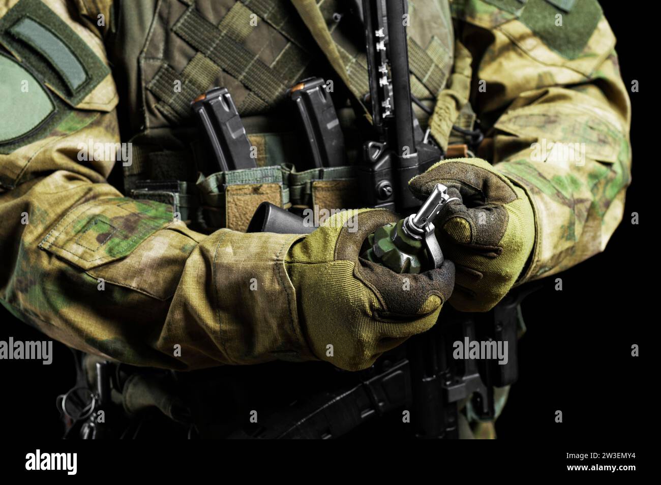 Soldier in full combat ammunition pulls a check from a grenade. Mixed ...