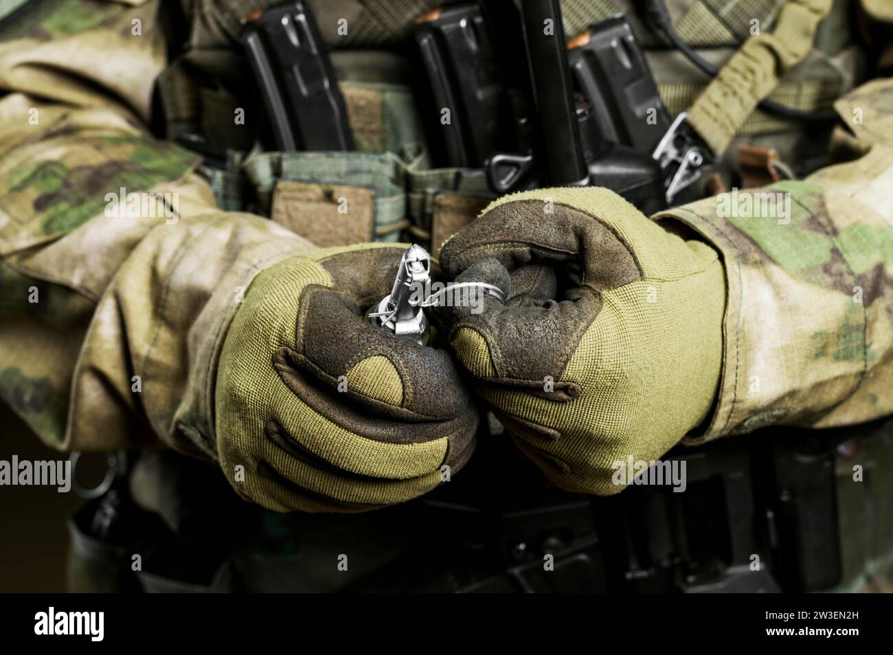 Soldier in full combat ammunition pulls a check from a grenade. Mixed ...