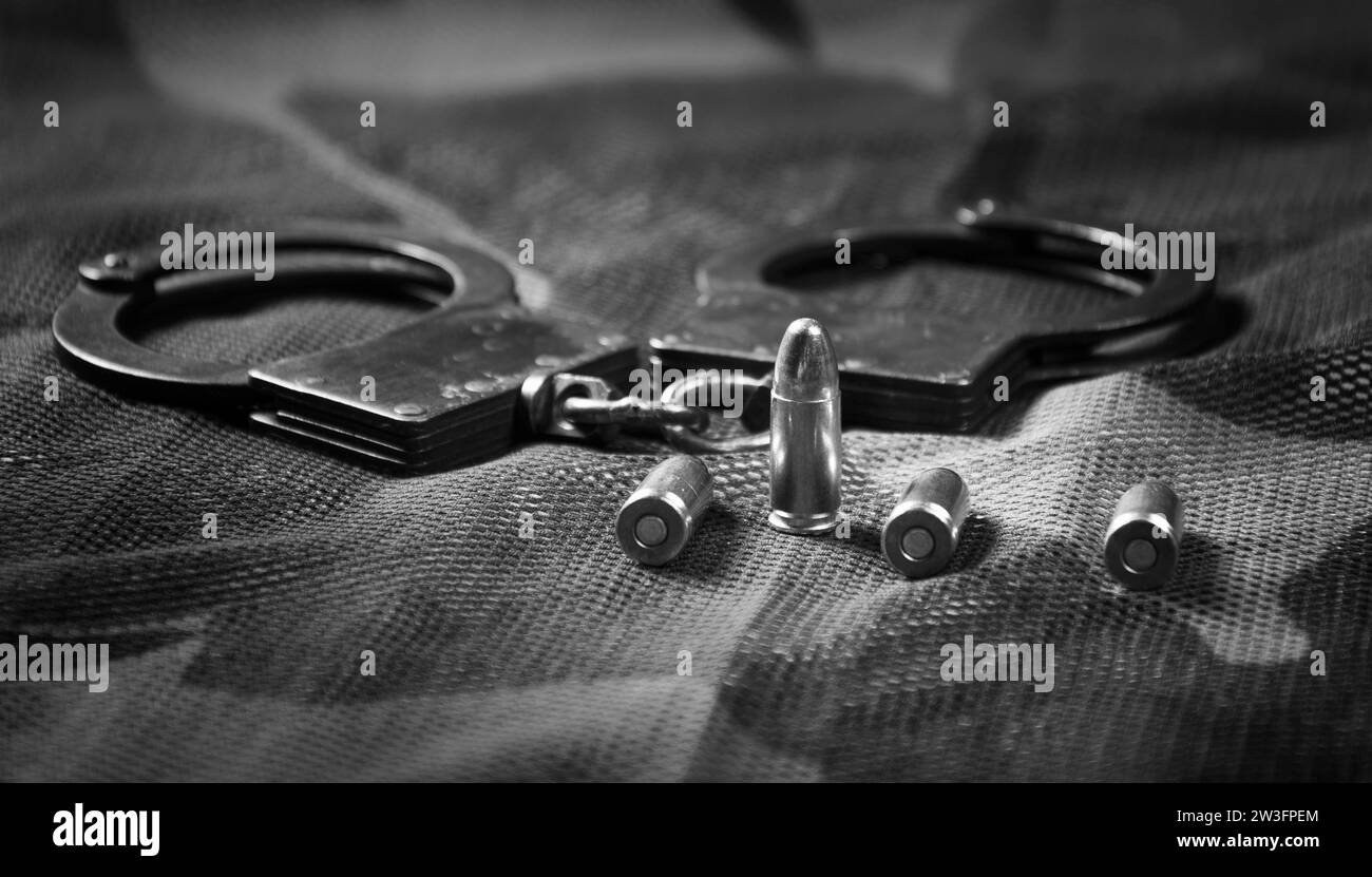 The handcuff and cartridges lie on a camouflage background. The concept ...