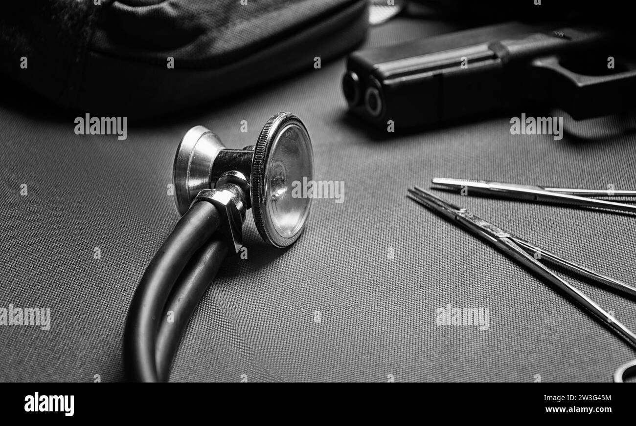 First aid kit, phonendoscope, set of scissors with a gun lie on a green ...