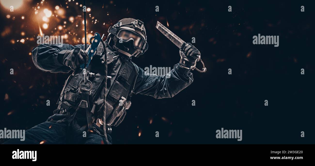 Man in military uniform hangs from a rope and swings a special device ...