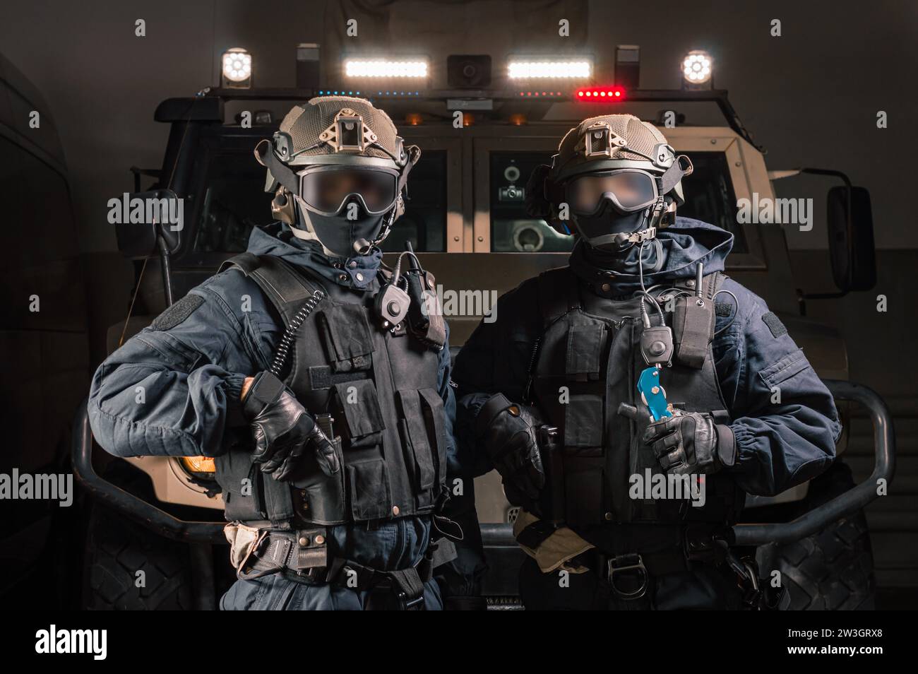 Two men in military uniforms stand in a hangar with a truck in the ...