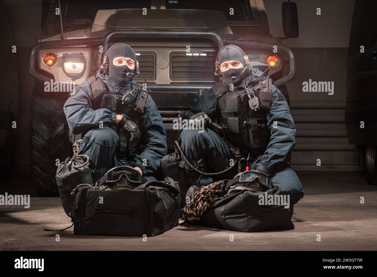 Two uniformed commandos sit in a hangar with a military truck in the ...