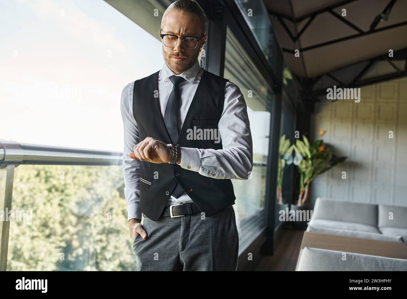 elegant professional with dapper style with glasses looking at his wristwatch, business concept ...