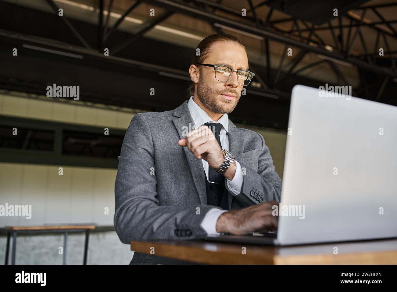 appealing refined man in gray smart suit with glasses and tie working ...