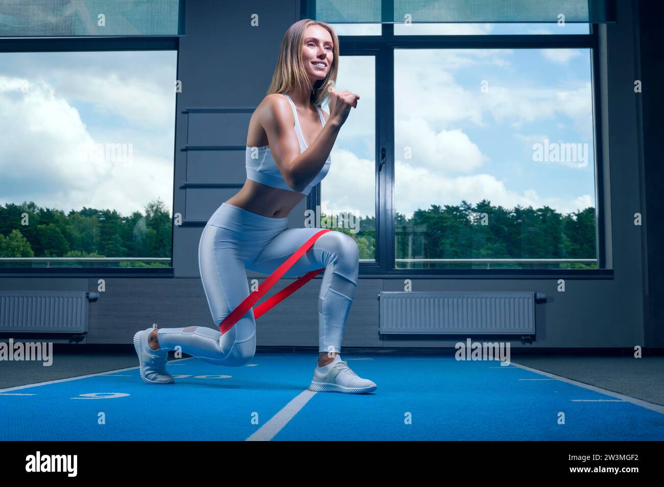Charming girl does an exercise called lunges. Elastic band for training ...