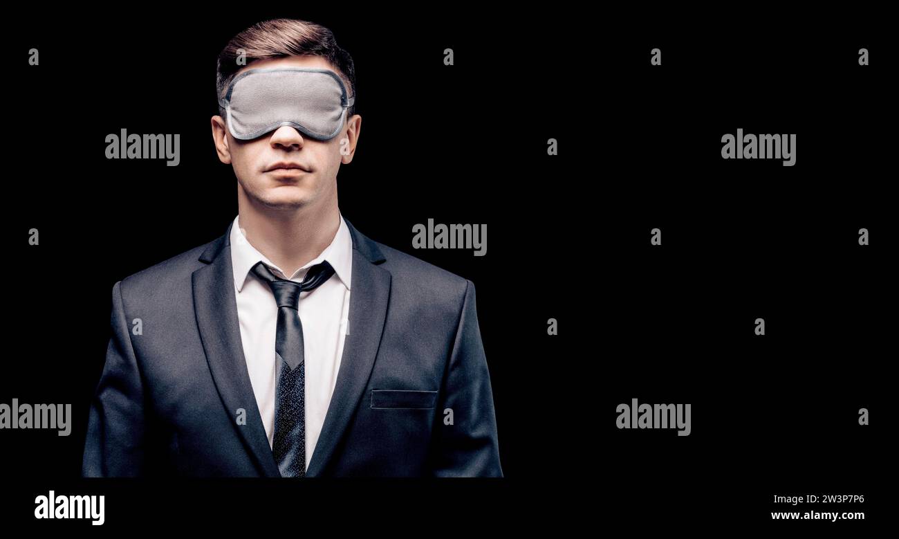 Portrait of a man in a mask for sleeping. He stands against a black ...