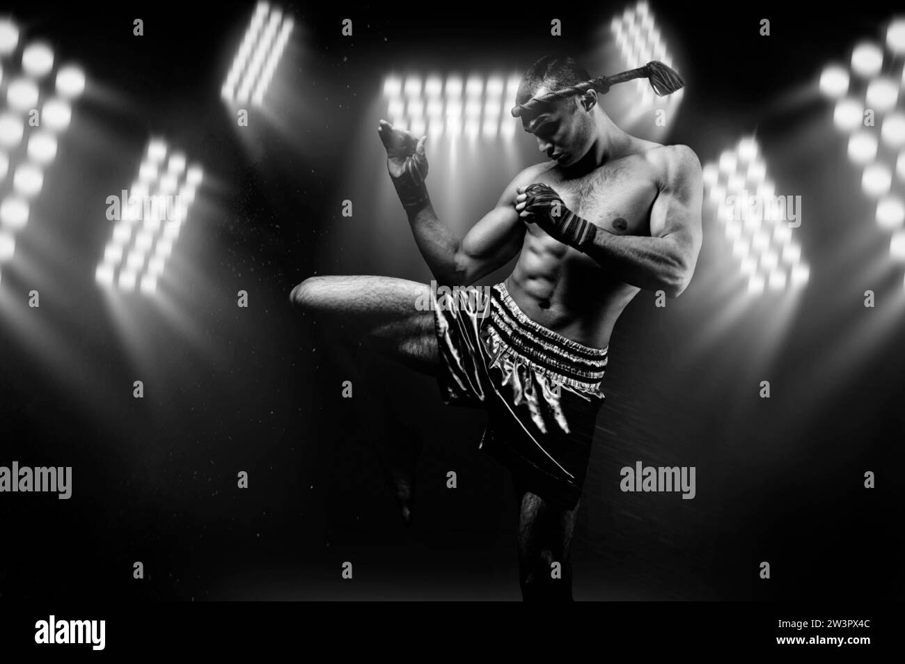 Kickboxer in the ring surrounded by searchlights stretches before the ...