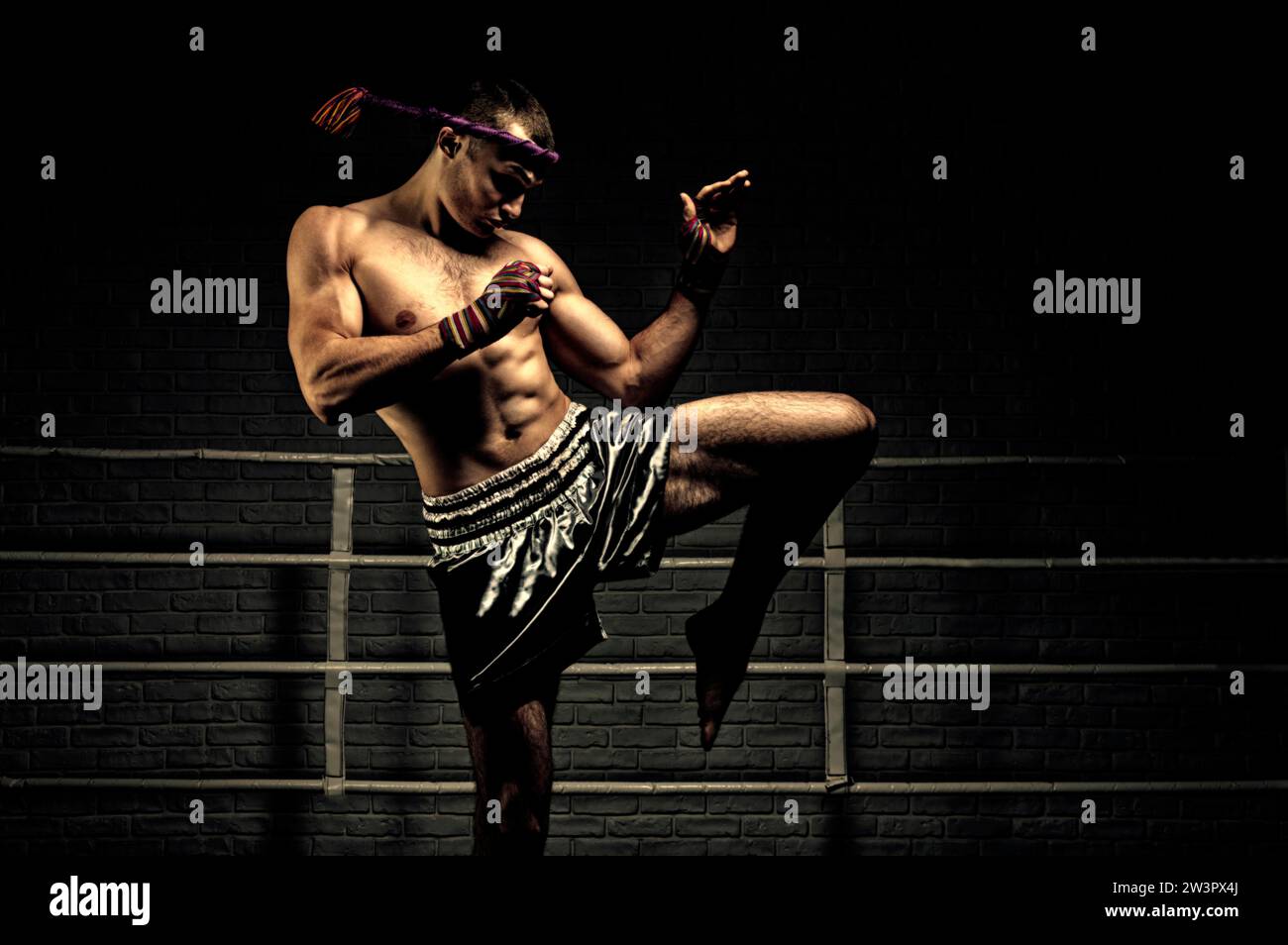 Kickboxer in the ring surrounded by searchlights stretches before the ...