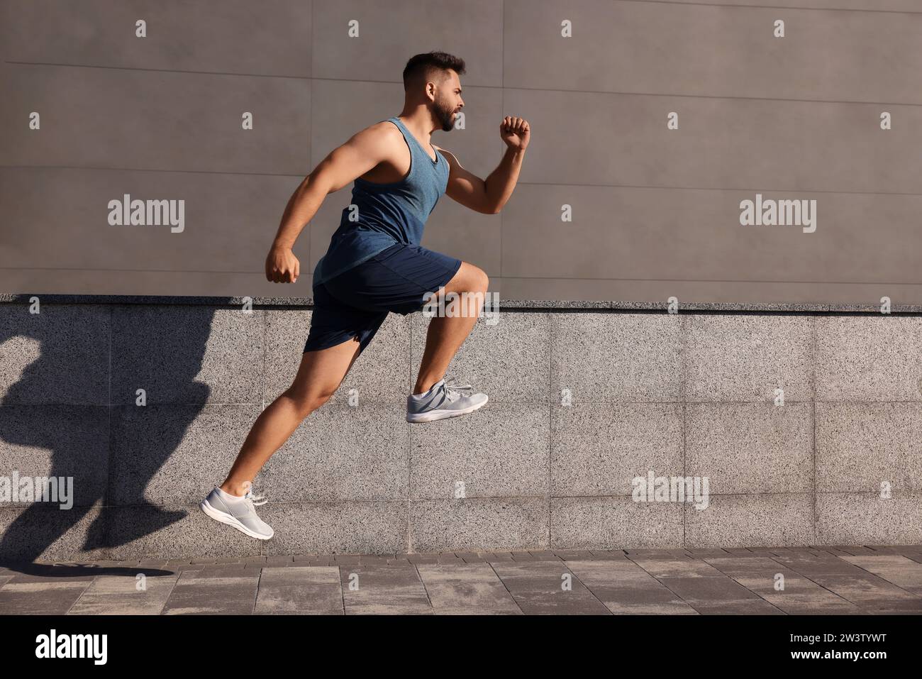 Young man running near building outdoors. Space for text Stock Photo ...