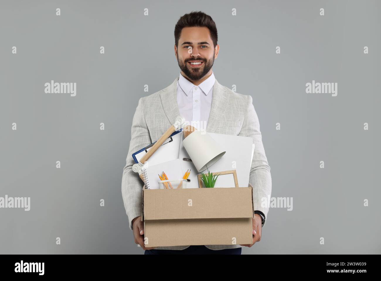 Happy unemployed man with box of personal office belongings on light ...