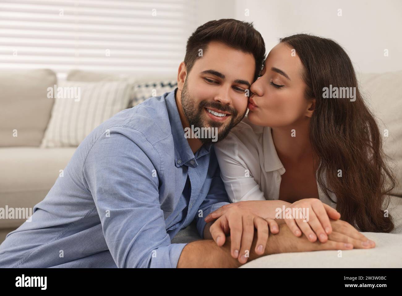 Young woman kissing her boyfriend at home Stock Photo - Alamy
