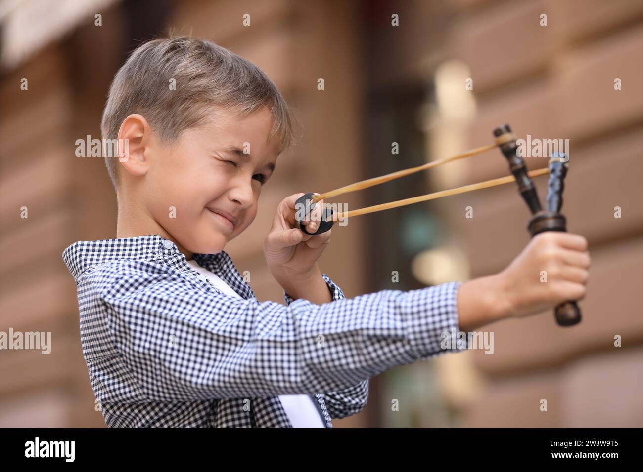 Little boy playing with slingshot outdoors on city street Stock Photo ...