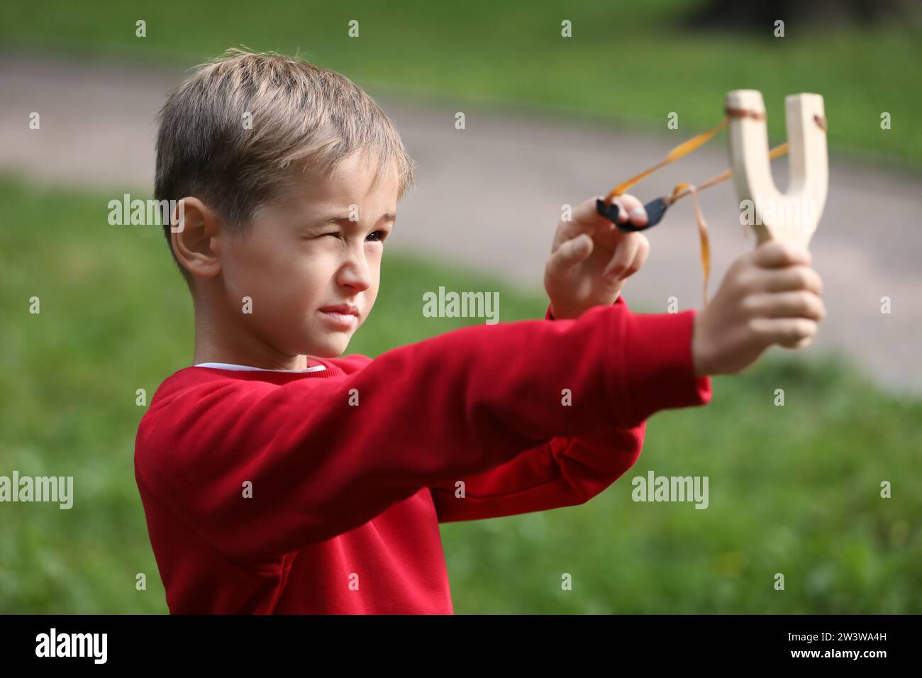 Little boy playing with slingshot in park Stock Photo - Alamy