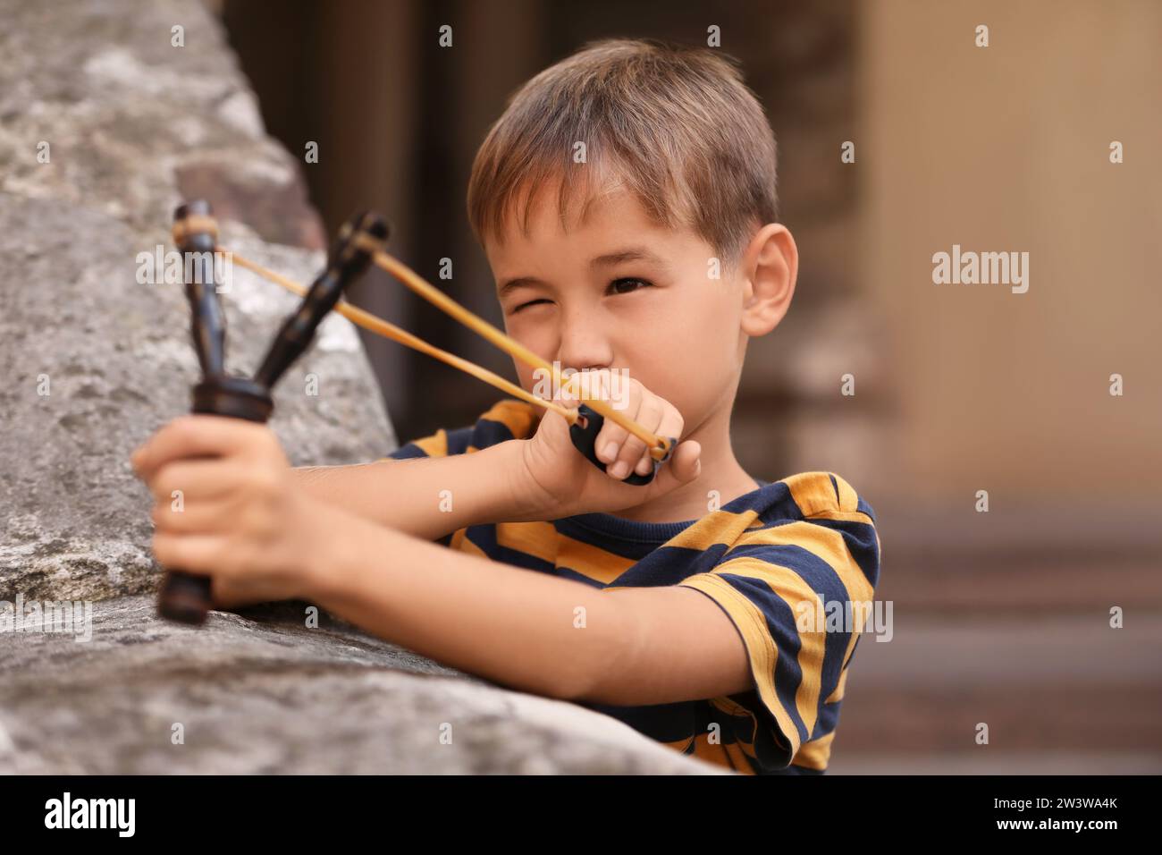 Cute little boy playing with slingshot outdoors Stock Photo - Alamy