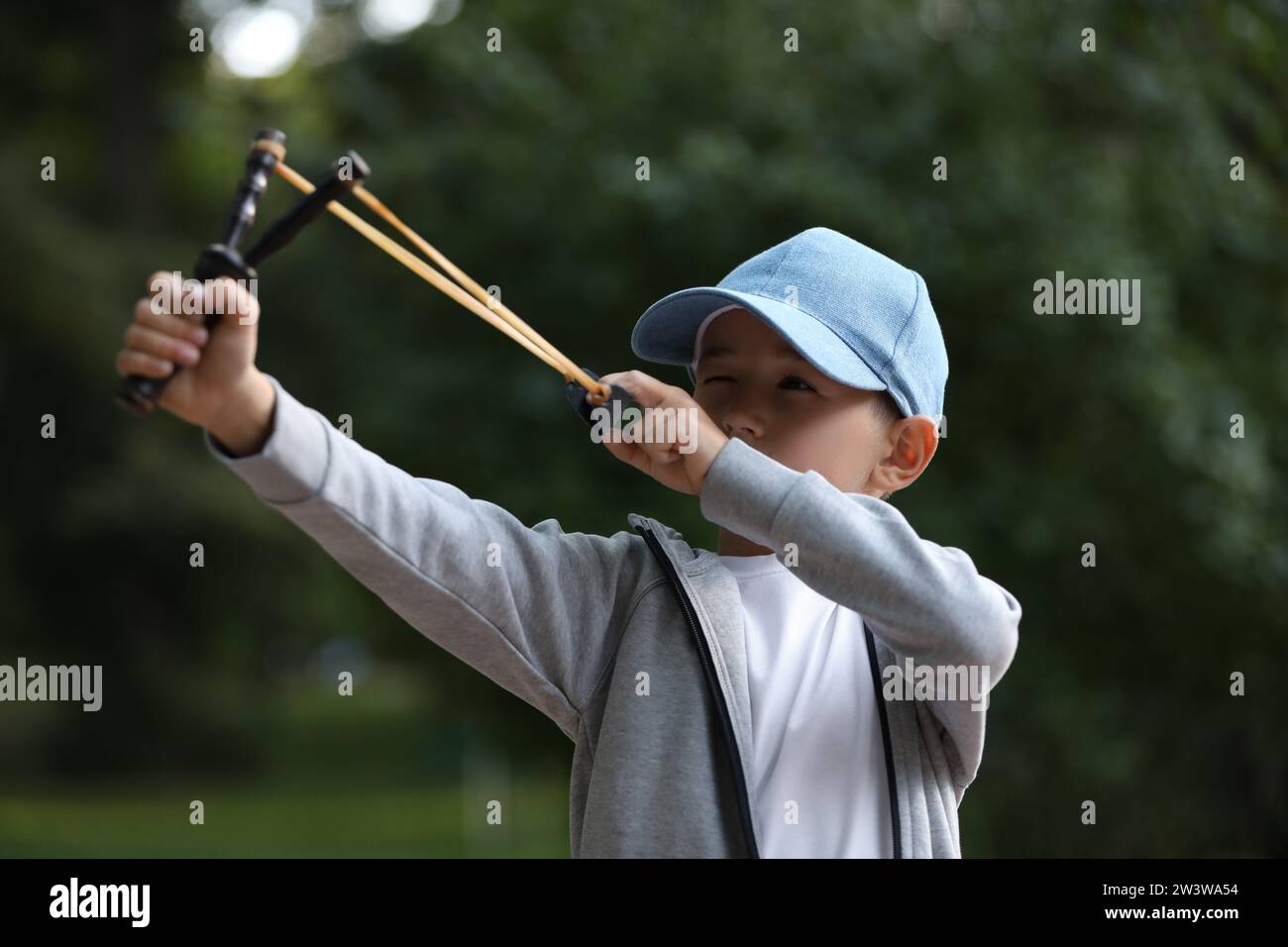 Little boy playing with slingshot in park Stock Photo - Alamy