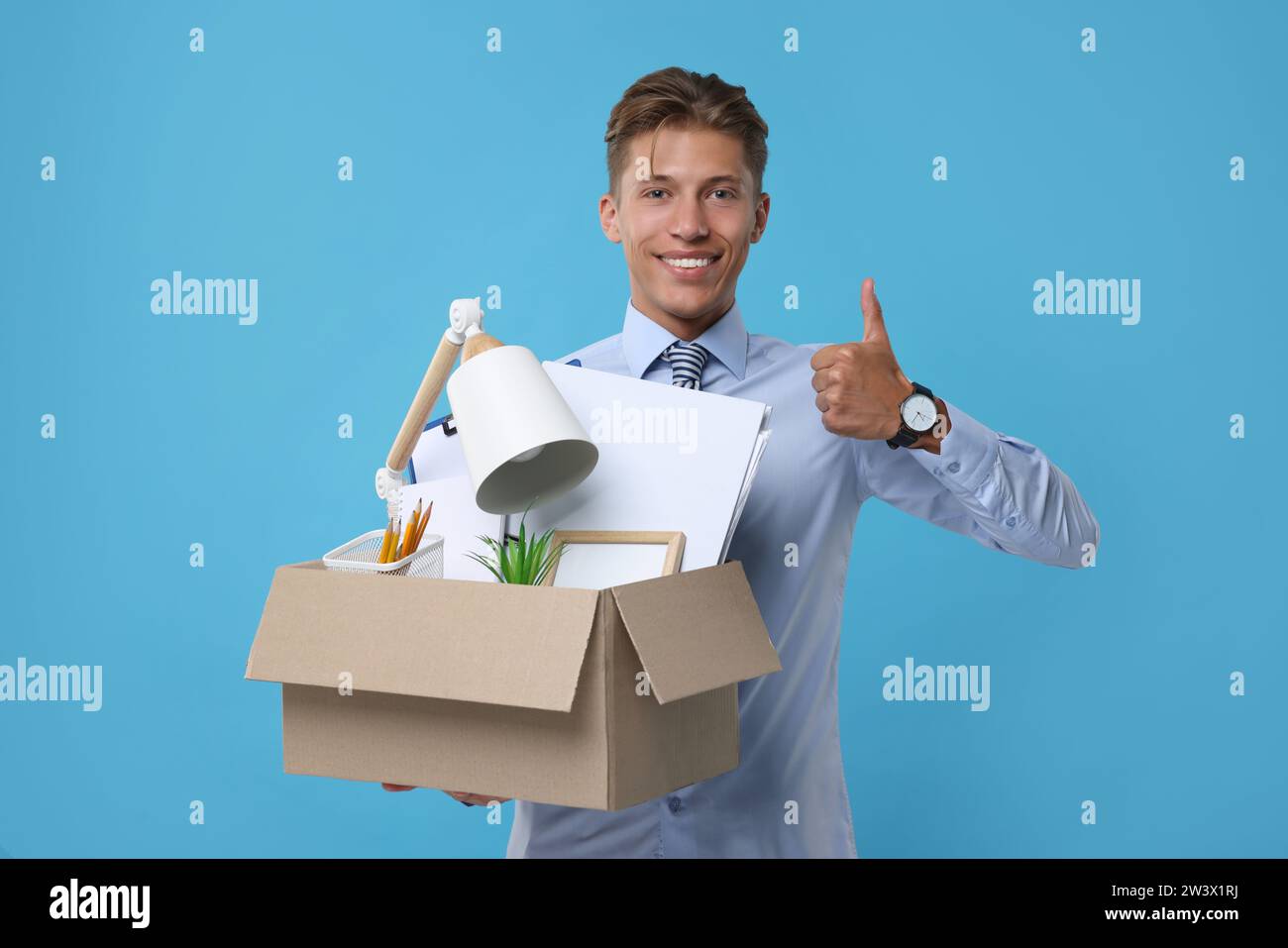 Happy unemployed young man with box of personal office belongings ...