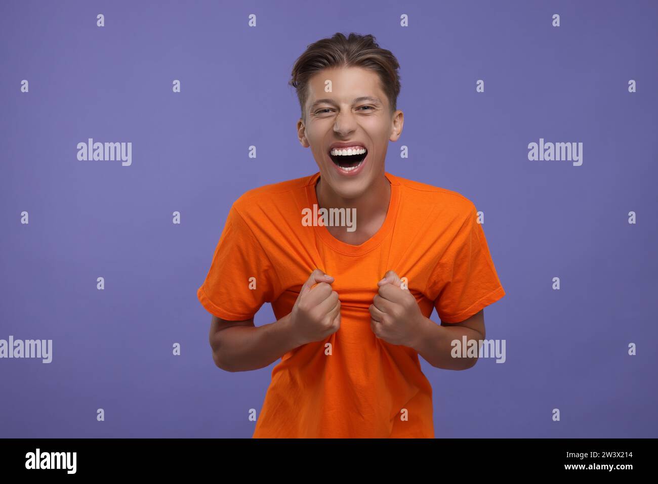 Emotional sports fan celebrating on purple background Stock Photo - Alamy