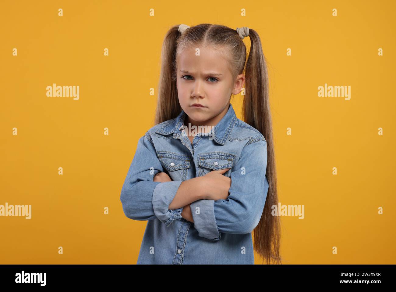 Resentful girl with crossed arms on orange background Stock Photo - Alamy