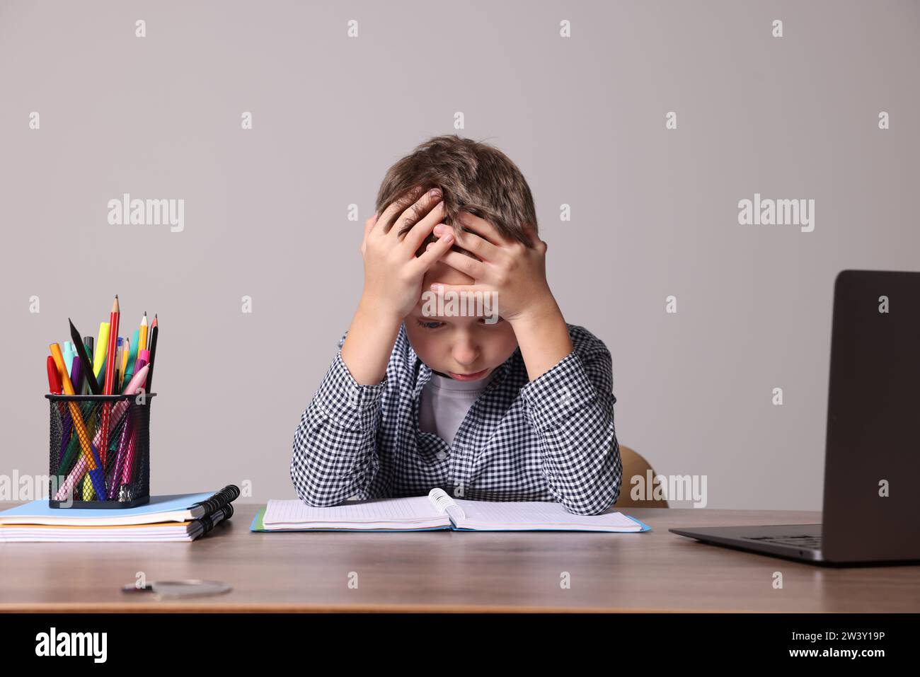 Little boy with stationery suffering from dyslexia at wooden table ...