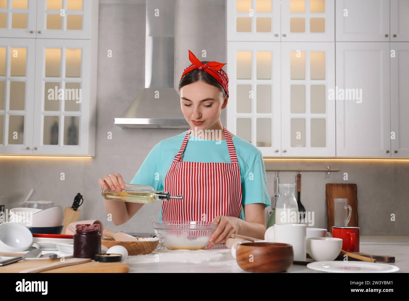 Beautiful woman cooking in kitchen. Dirty dishware, food leftovers and ...