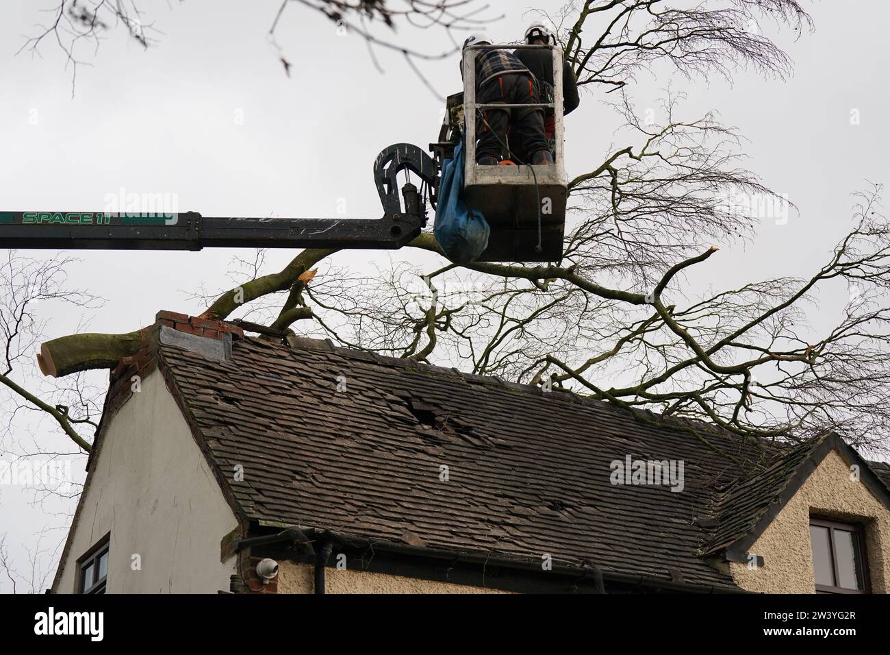 Workmen in a cherry picker remove a fallen tree which has damaged the ...