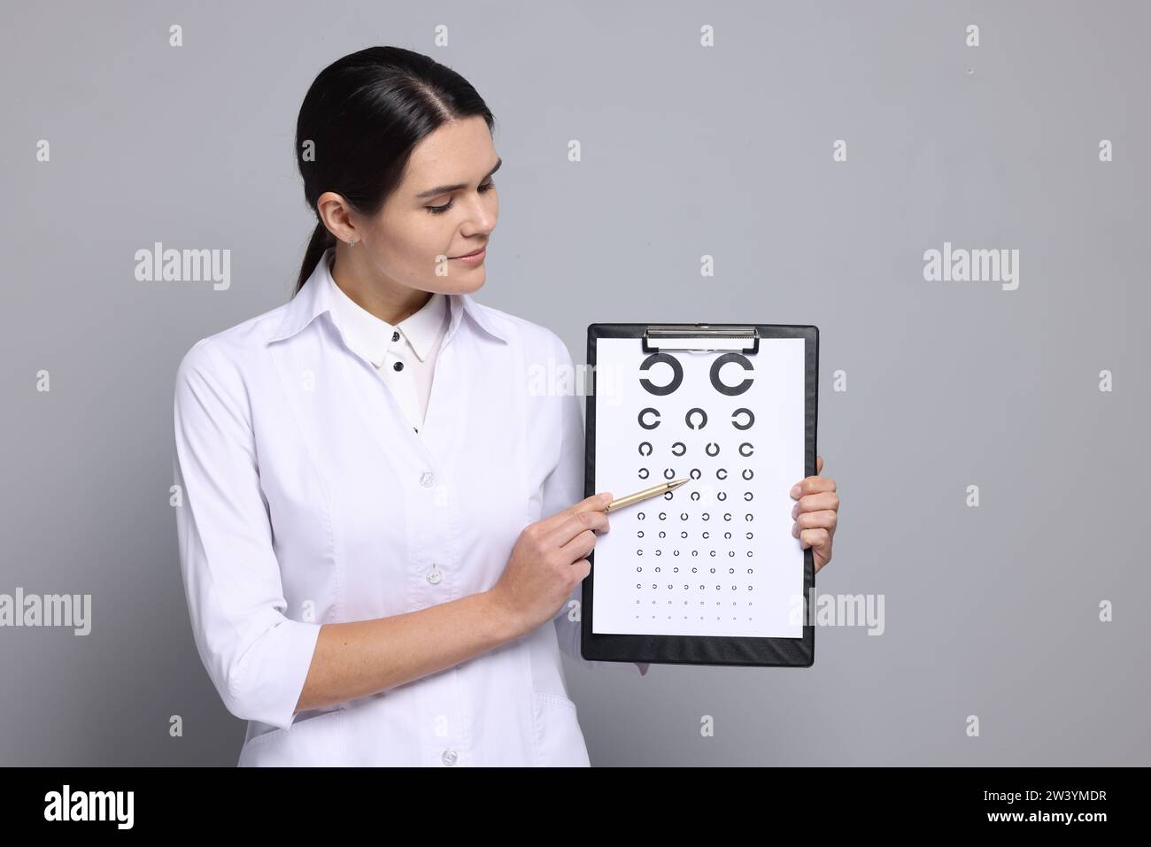 Ophthalmologist pointing at vision test chart on gray background Stock ...