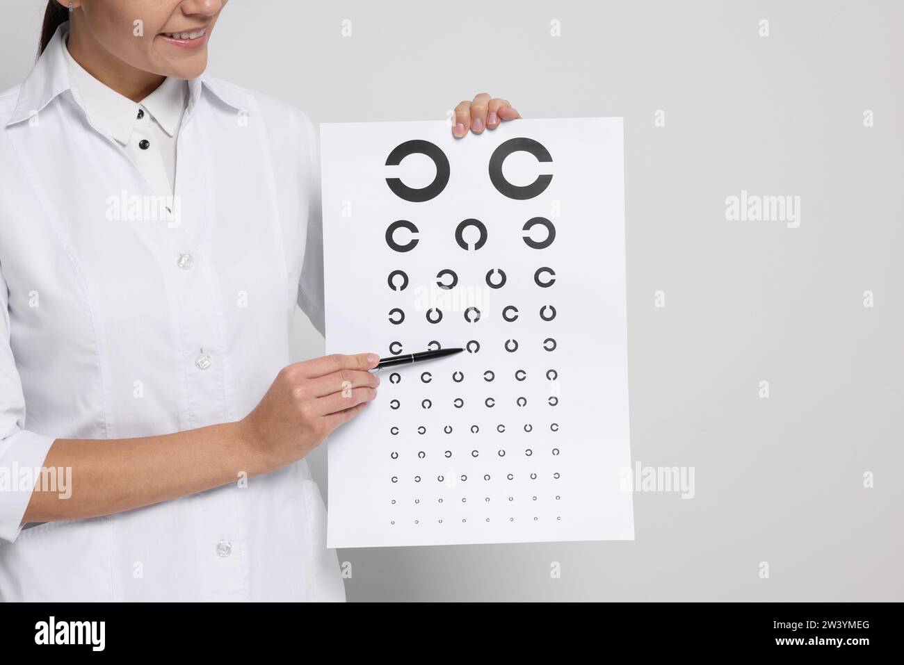 Ophthalmologist pointing at vision test chart on light background ...