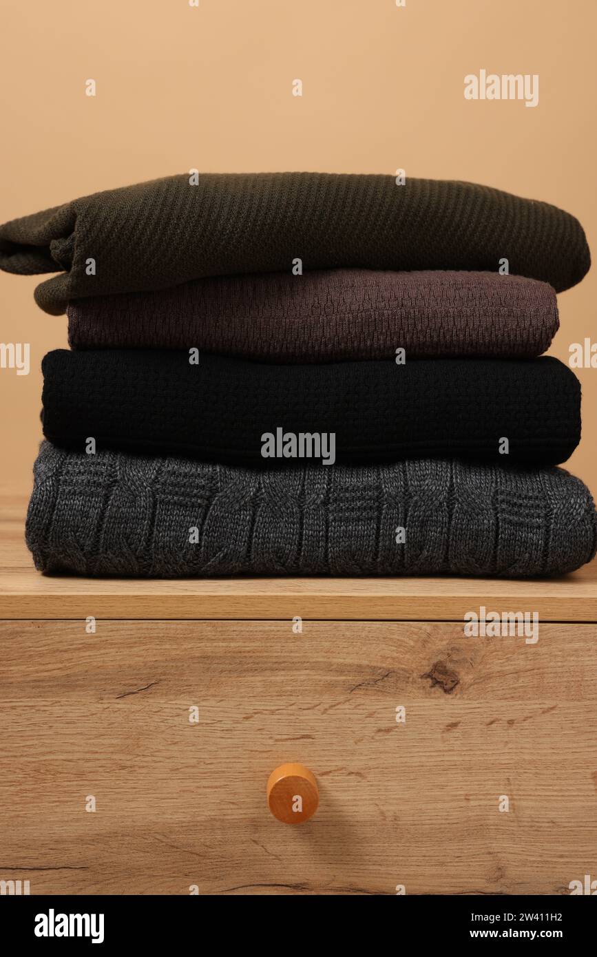 Different casual sweaters on chest of drawers against light brown ...