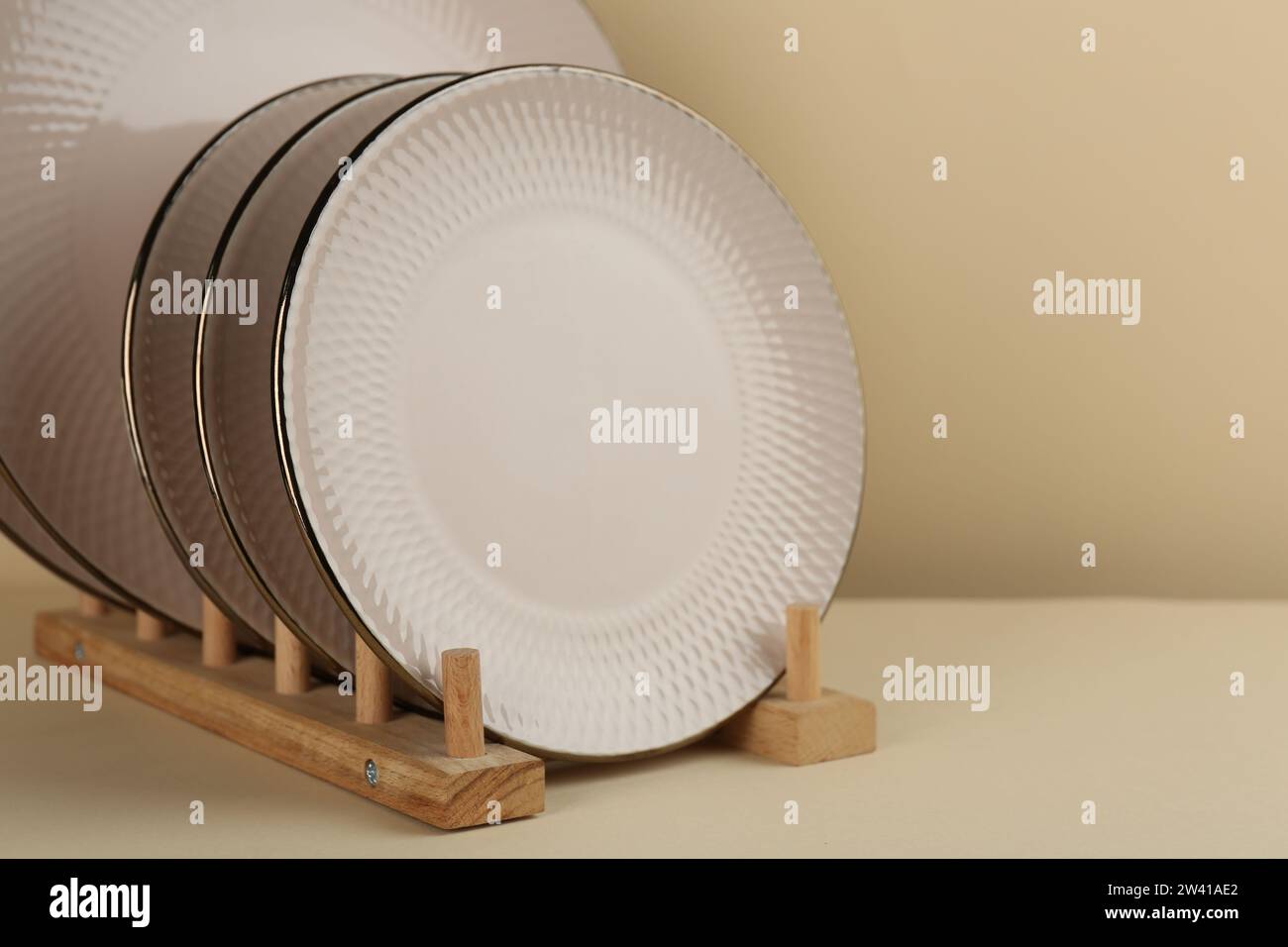 Drying rack with beige ceramic plates on pale yellow table, closeup ...