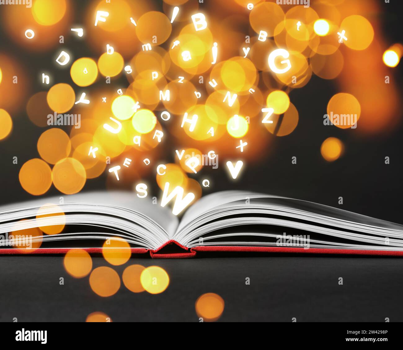 Letters flying out from open book on black background, closeup. Bokeh ...