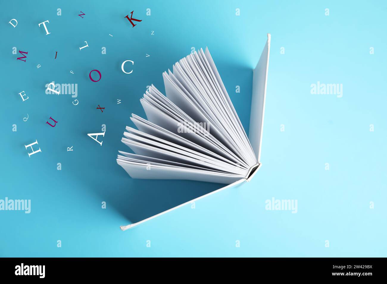 Open book with letters flying out of it on light blue background, top ...