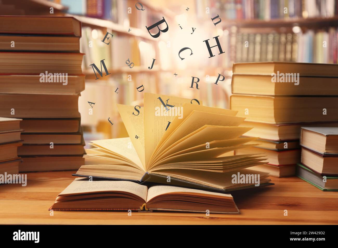 Open book with letters flying out of it in library Stock Photo - Alamy