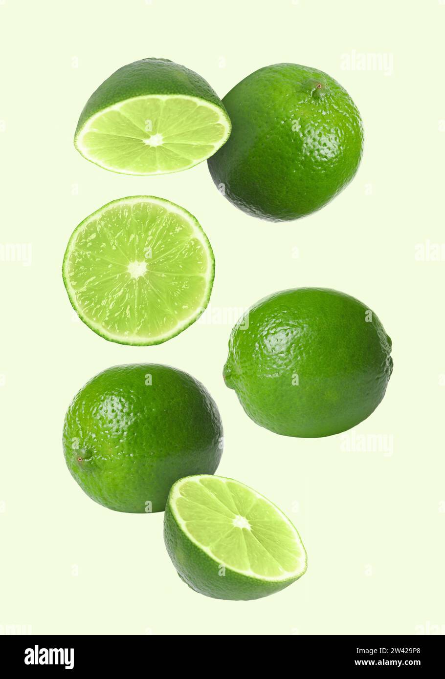 Fresh ripe limes falling on light green background Stock Photo - Alamy