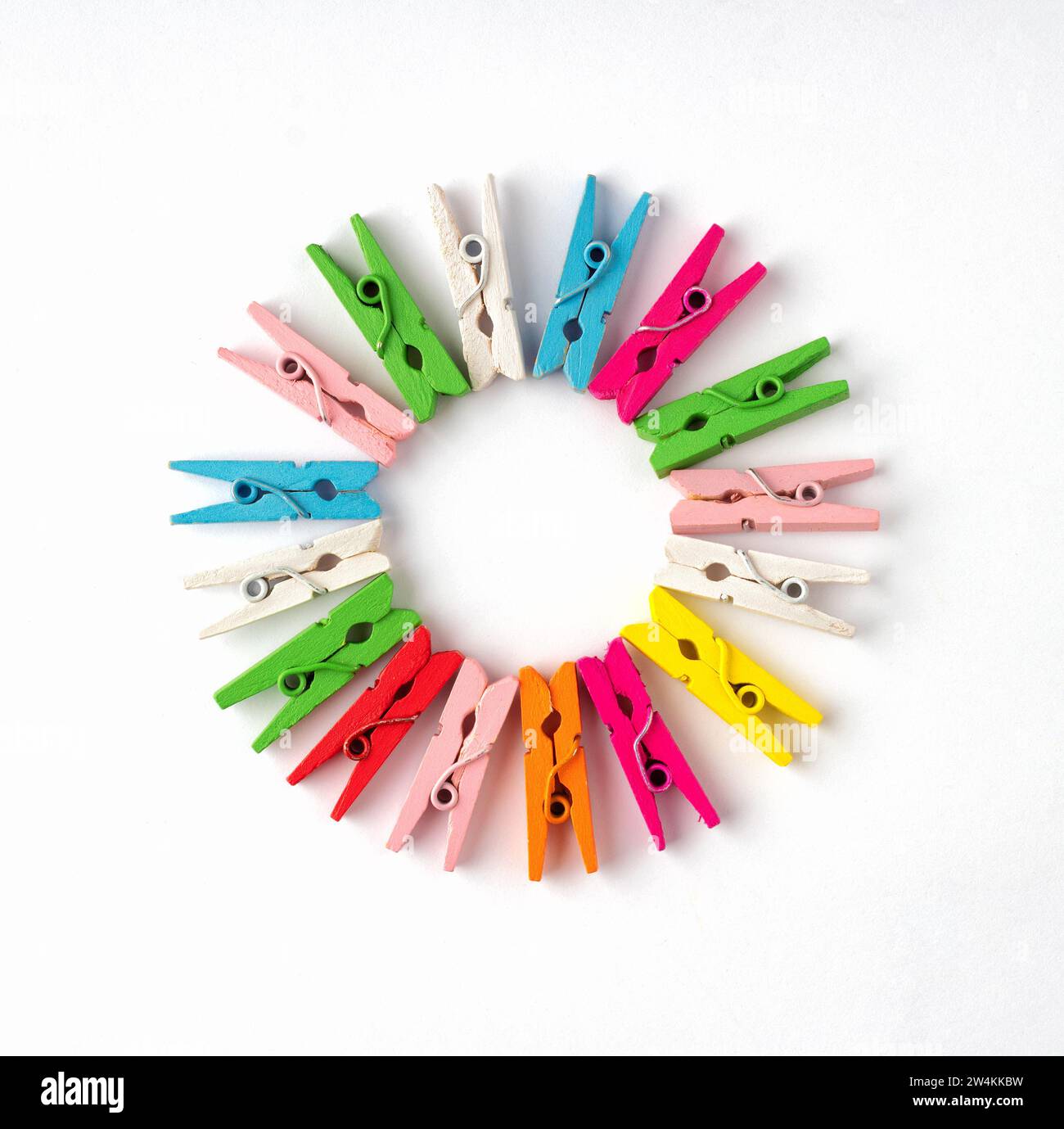 Set of wooden multi-colored clothespins lying in a circle on white ...