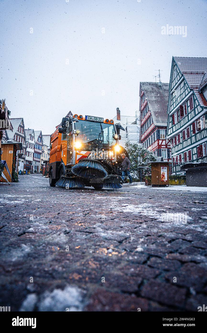 Clearing vehicle on a snow-covered road at a Christmas market at dusk ...
