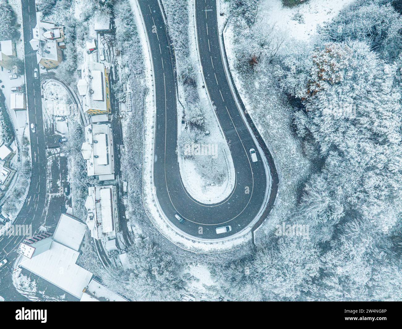 Snow-covered winding road surrounded by trees from a bird's eye view ...