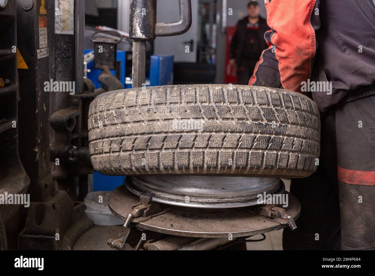 Car mechanic changing tire on the rim in service garage. Close-up of ...