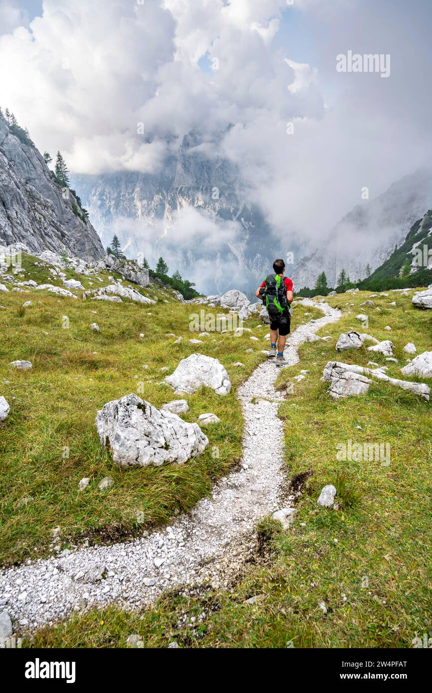 Mountaineer on a hiking trail, cloudy mountains, descent over the ...