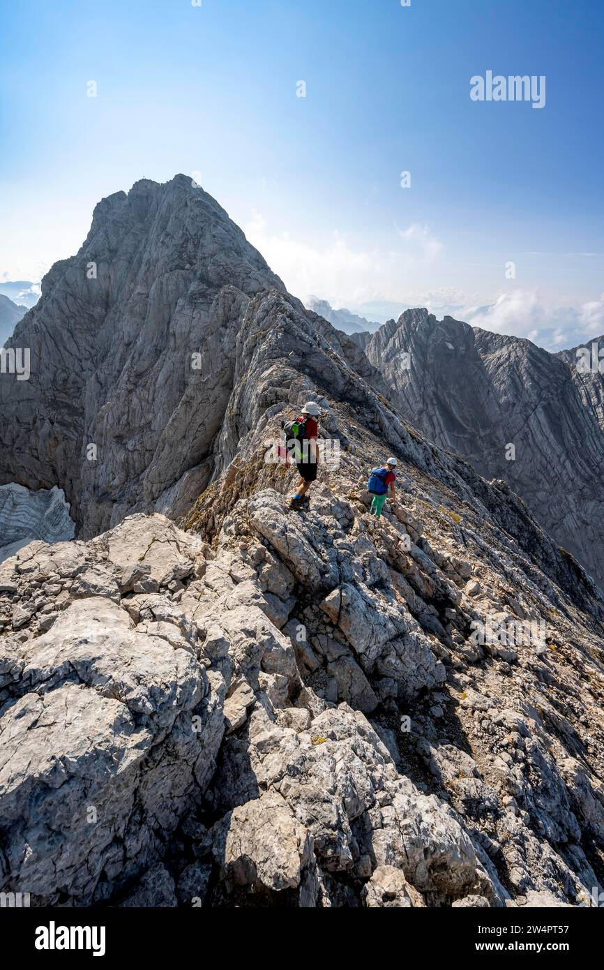 Two mountaineers on a rocky narrow mountain path, view of the summit of ...