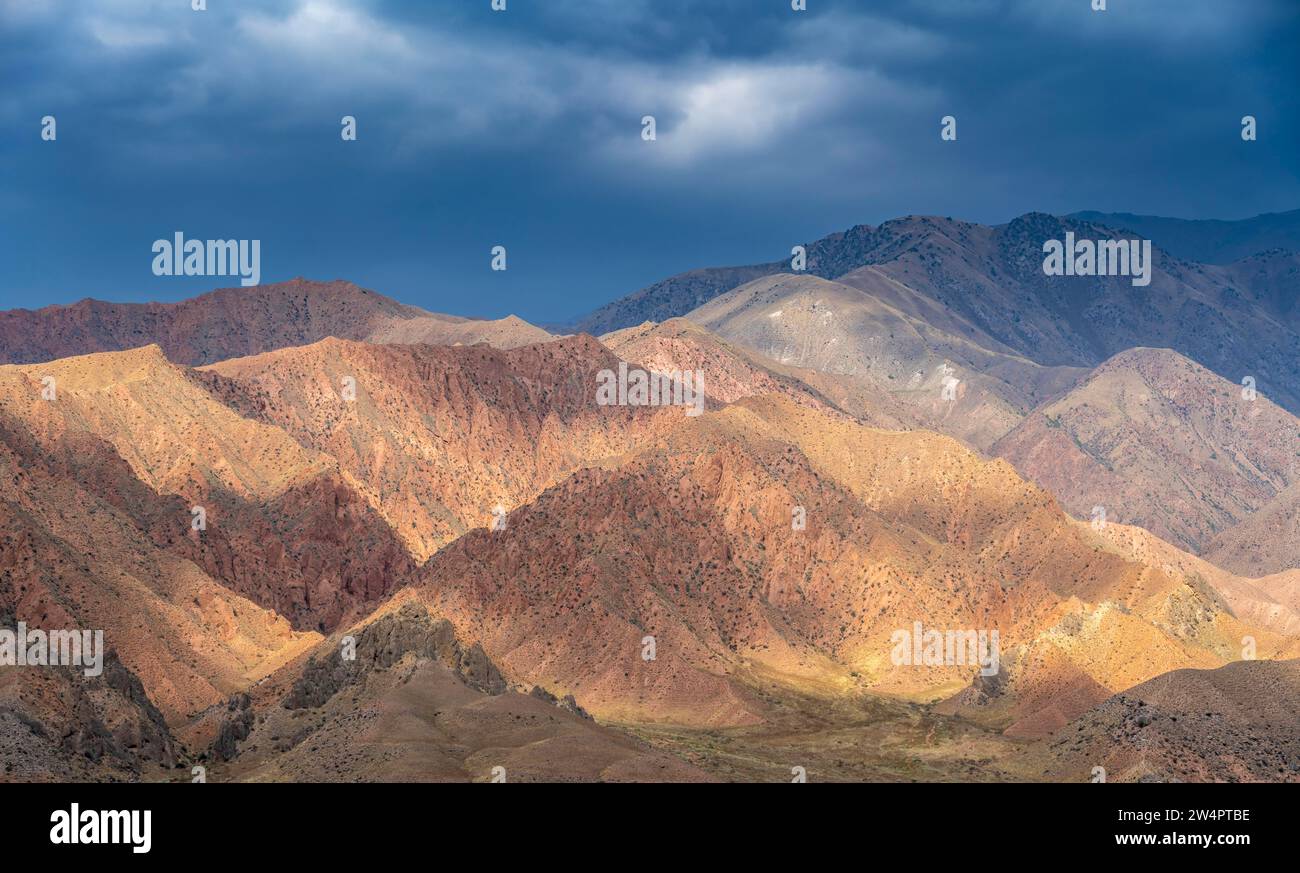 Red and orange mountains in atmospheric light, dramatic cloudy sky ...