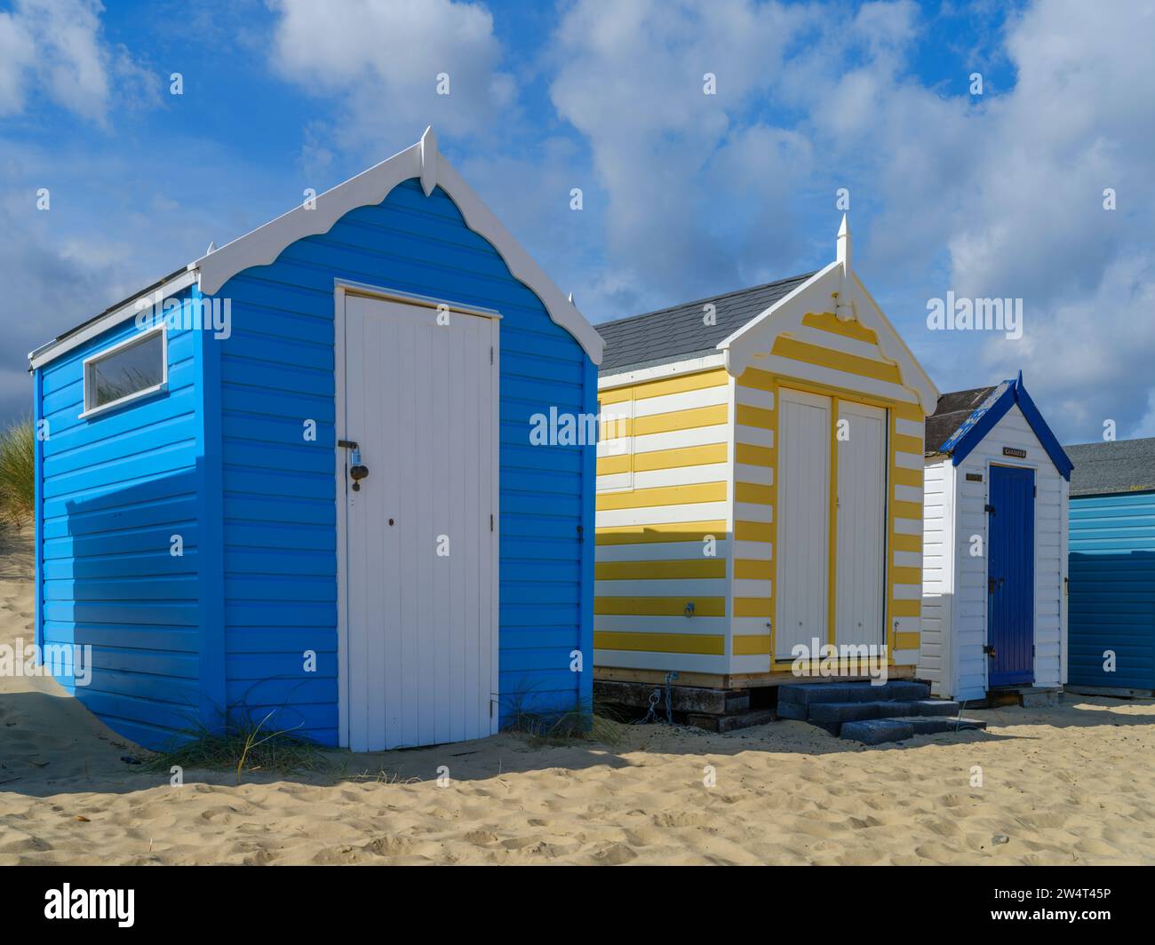 Summer in England. A line of iconic beach huts on the golden sands at ...