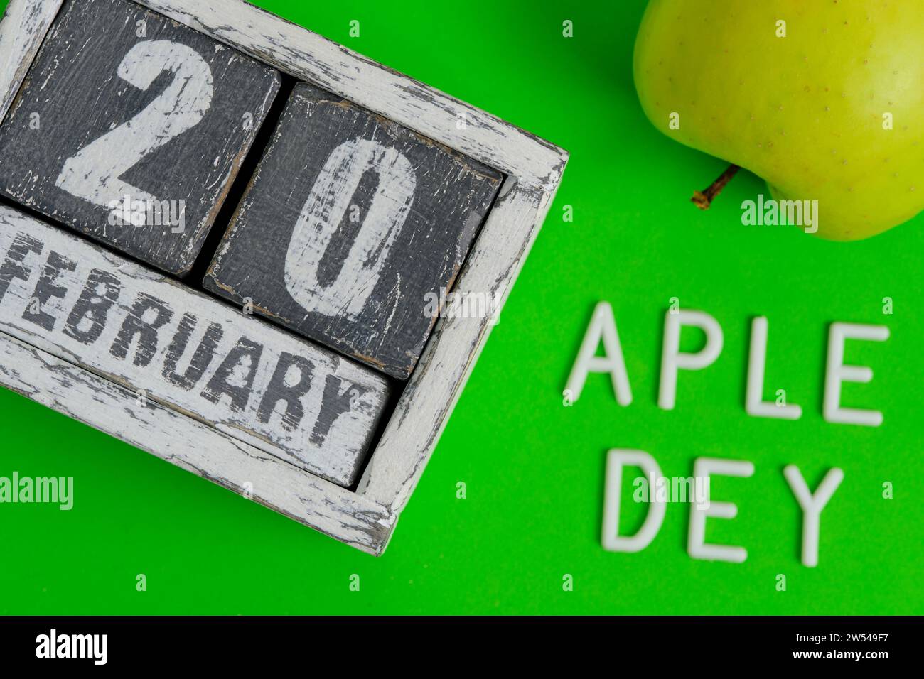February 20th on wooden calendar and green apple on green background ...