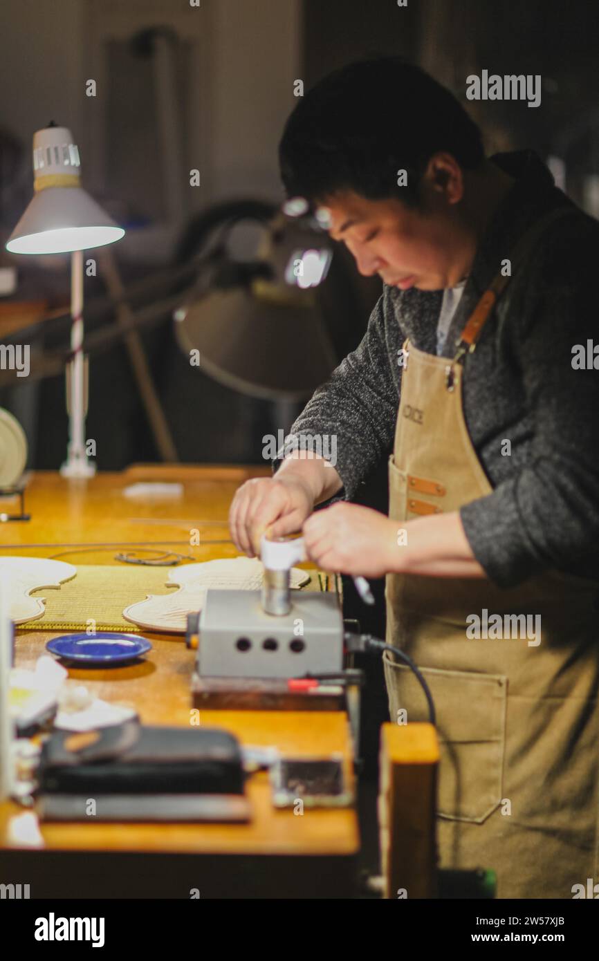 Asian Master luthier lute maker artisan both hands performing bend ...
