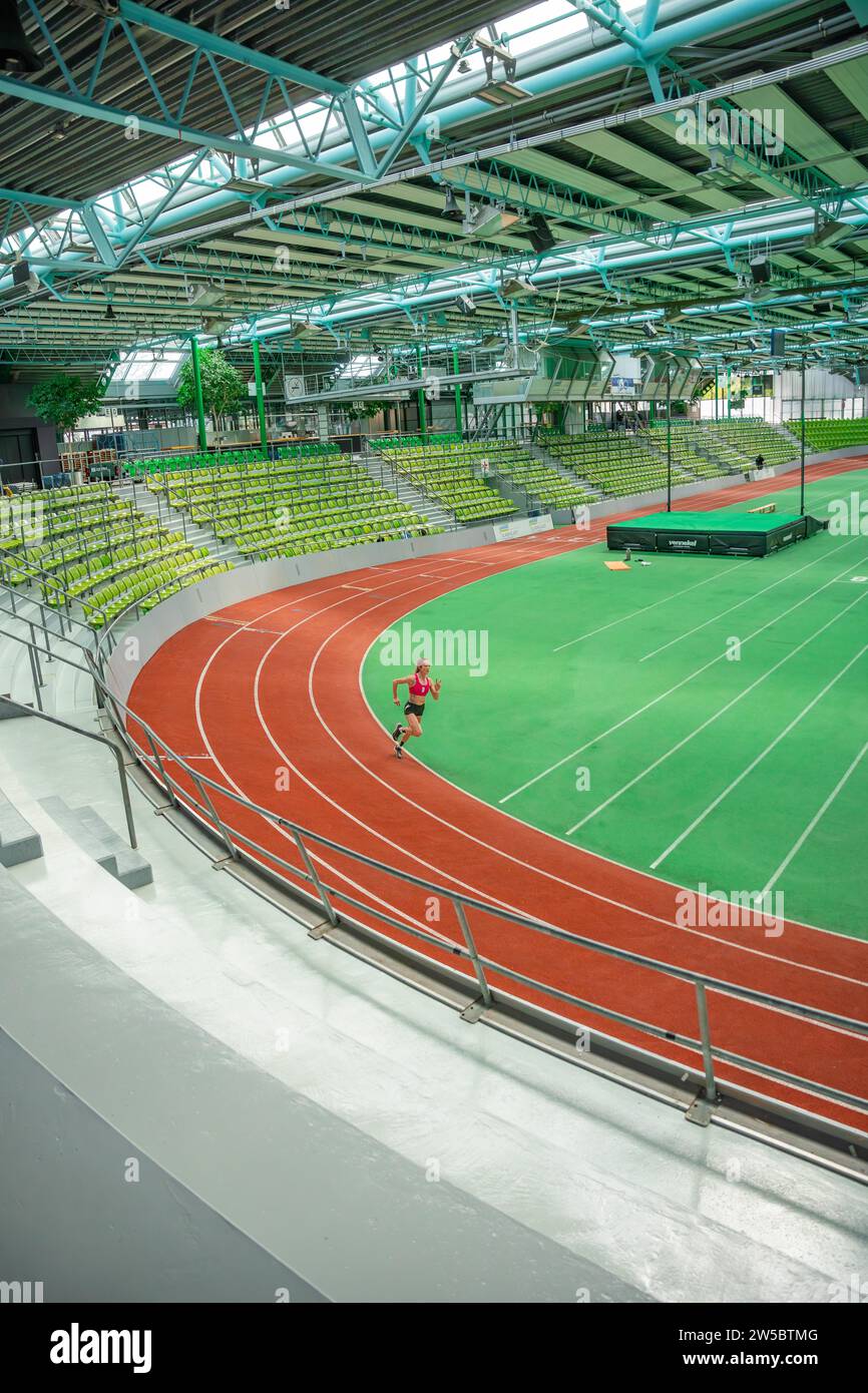 Person jogging in a stadium on a red running track, green pitch and ...