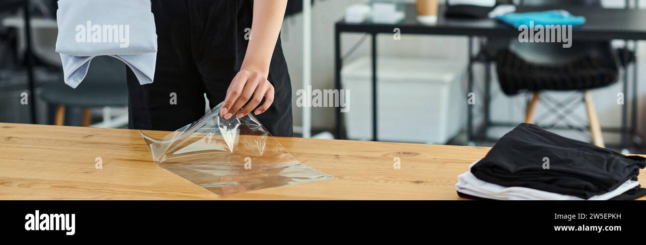 cropped view of woman packing neatly folded clothes in plastic bag on ...
