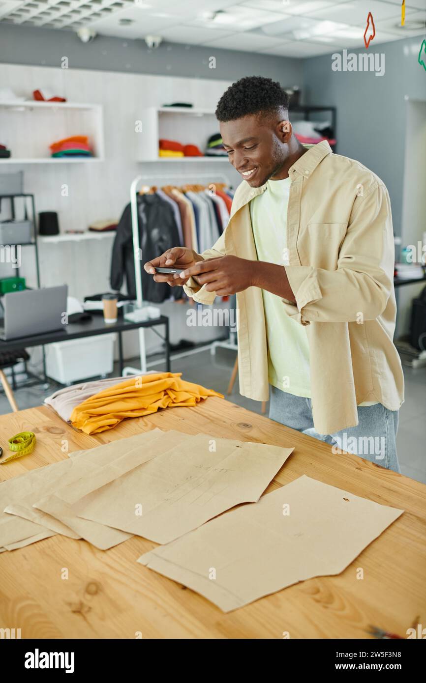 cheerful african american fashion designer taking photo of sewing ...